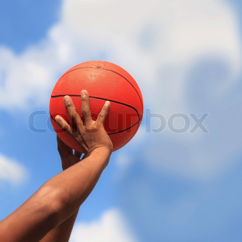 Basketball in hands on blue sky | Stock image | Colourbox