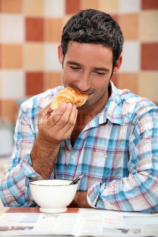 Smiling Mann isst Croissant zum ... | Stock Bild | Colourbox