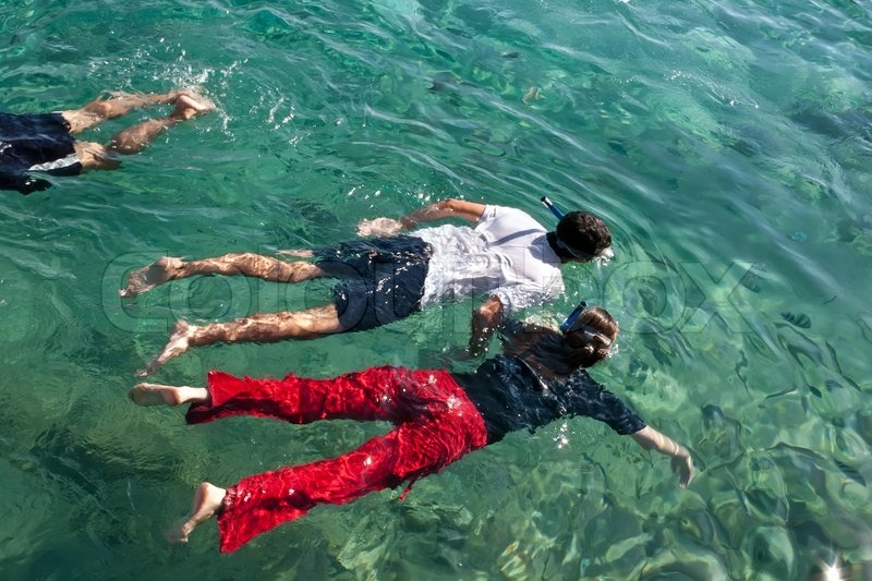 A young man and a woman swimming with snorkeling in the clothes on the ...
