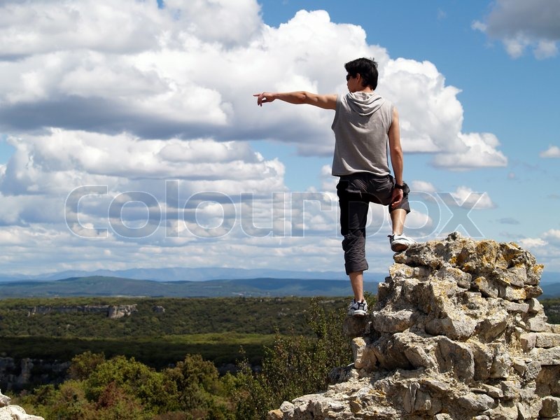 Hiker on mountain pointing towards ... | Stock image | Colourbox