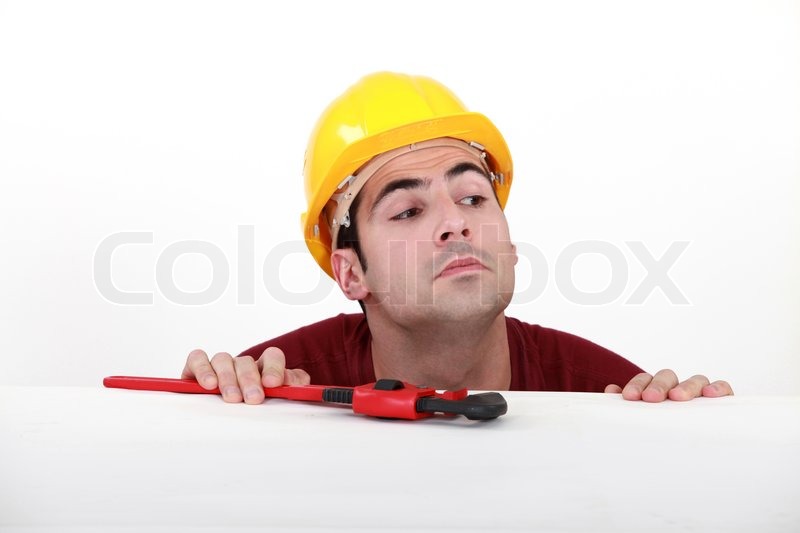 Curious tradesman peering over a ledge | Stock image | Colourbox
