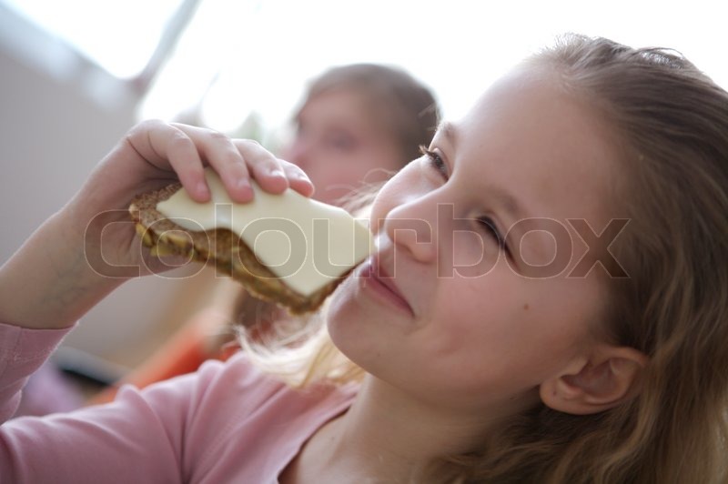 A happy girl eating a cheese sandwich | Stock image | Colourbox