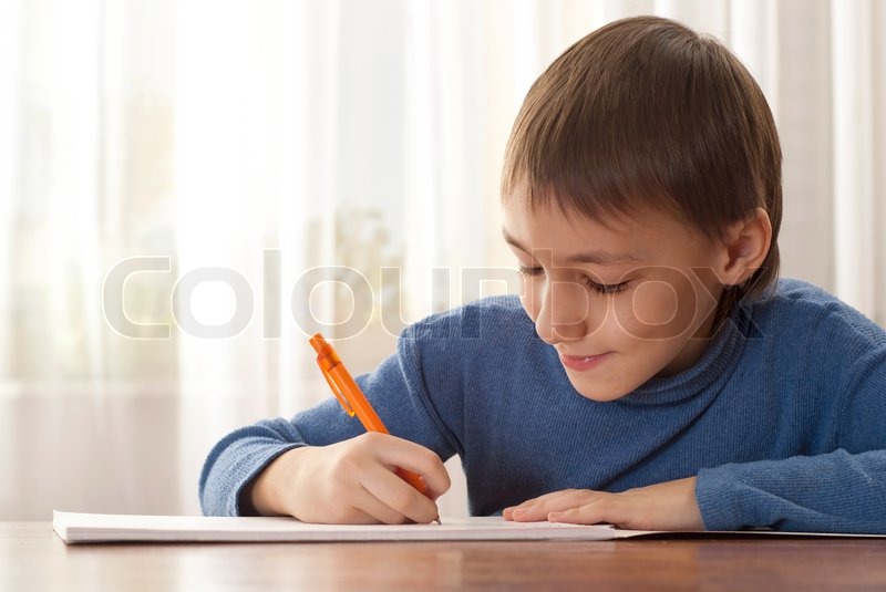 Little boy writing a book at the table | Stock image | Colourbox