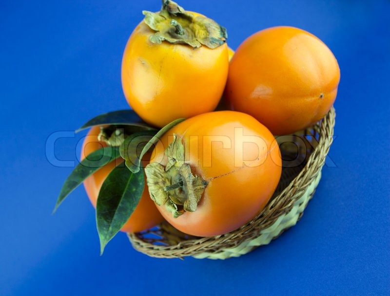 Persimmon fruit isolated on blue ... | Stock image | Colourbox